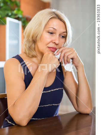 Sad mature woman sitting at table - Stock Photo [19363833] - PIXTA