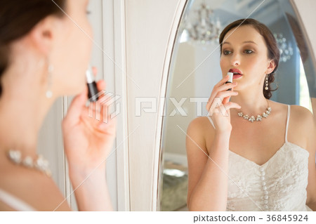 Side view of beautiful bride applying lipstick... - Stock Photo ...
