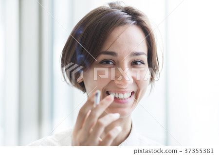 Smiling young woman smoking a cigarette - Stock Photo [37355381] - PIXTA