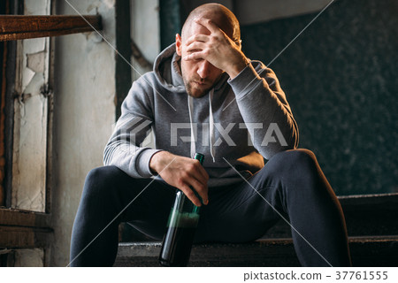 Male robber with bottle of alcohol sits on stairs - Stock Photo ...