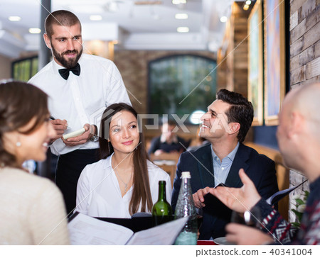 Waiter with notebook taking order from friendly... - Stock Photo ...