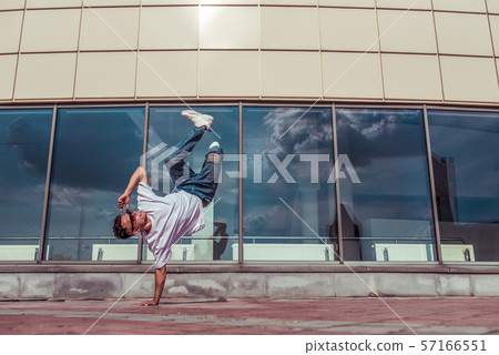 strong sporty man dancing break dance, stands one arm red-haired, young ...