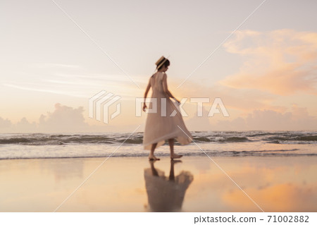 A woman walking along the beach - Stock Photo [71002882] - PIXTA