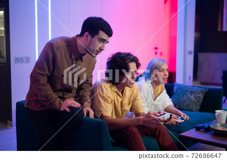 Young friends play video games while sitting on... - Stock Photo ...