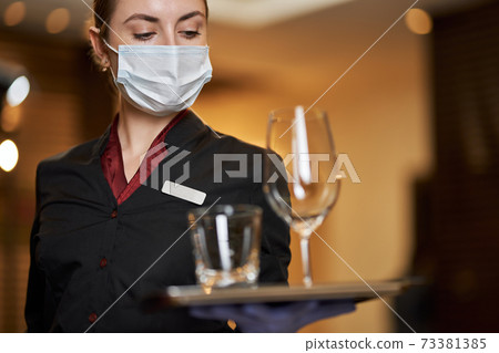 Efficient waitress using protective mask while... - Stock Photo ...