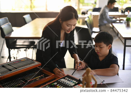Smiling asian teacher helping children coloring... - Stock Photo ...