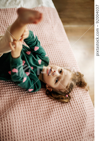 A cute little girl is lying on the bed with her... - Stock Photo ...