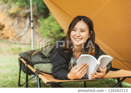 Young female camper reading a book while... - Stock Photo [116302513 ...